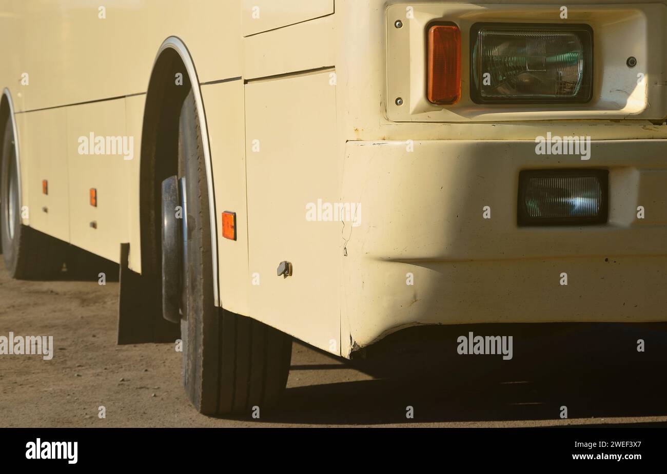 Photo of the hull of a large and long yellow bus. Close-up front view ...