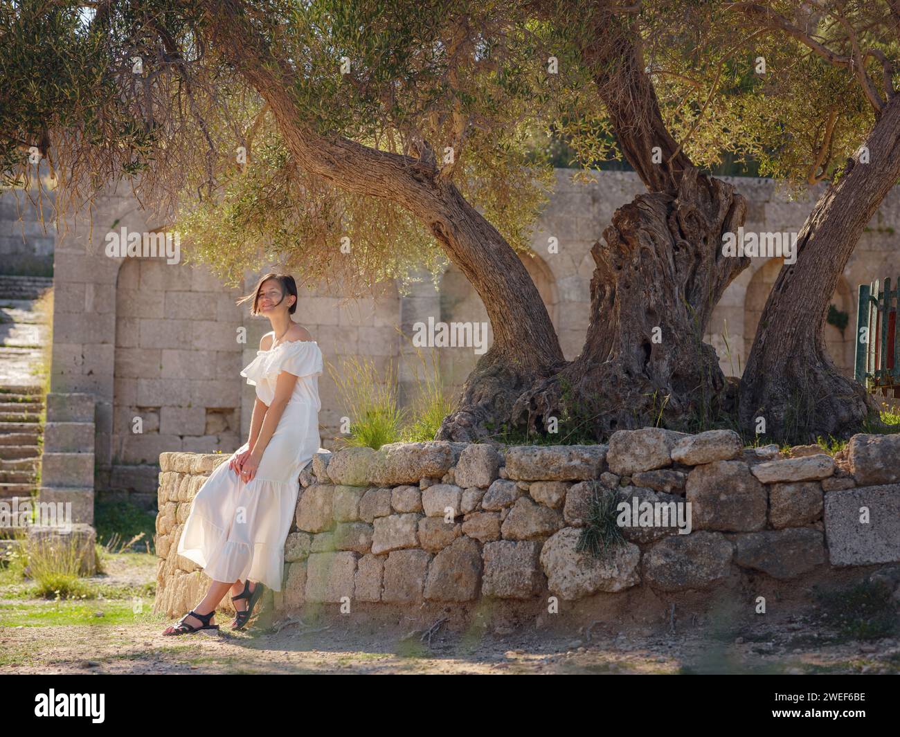 Beautiful Asian young woman in white dress outdoor. Acropolis of Rhodes ...