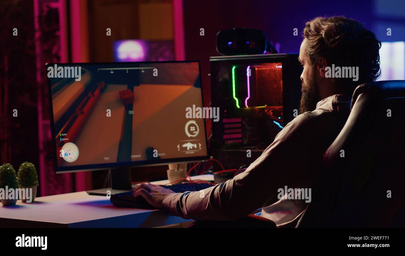 Man in dark living room playing videogame on gaming PC at computer desk ...