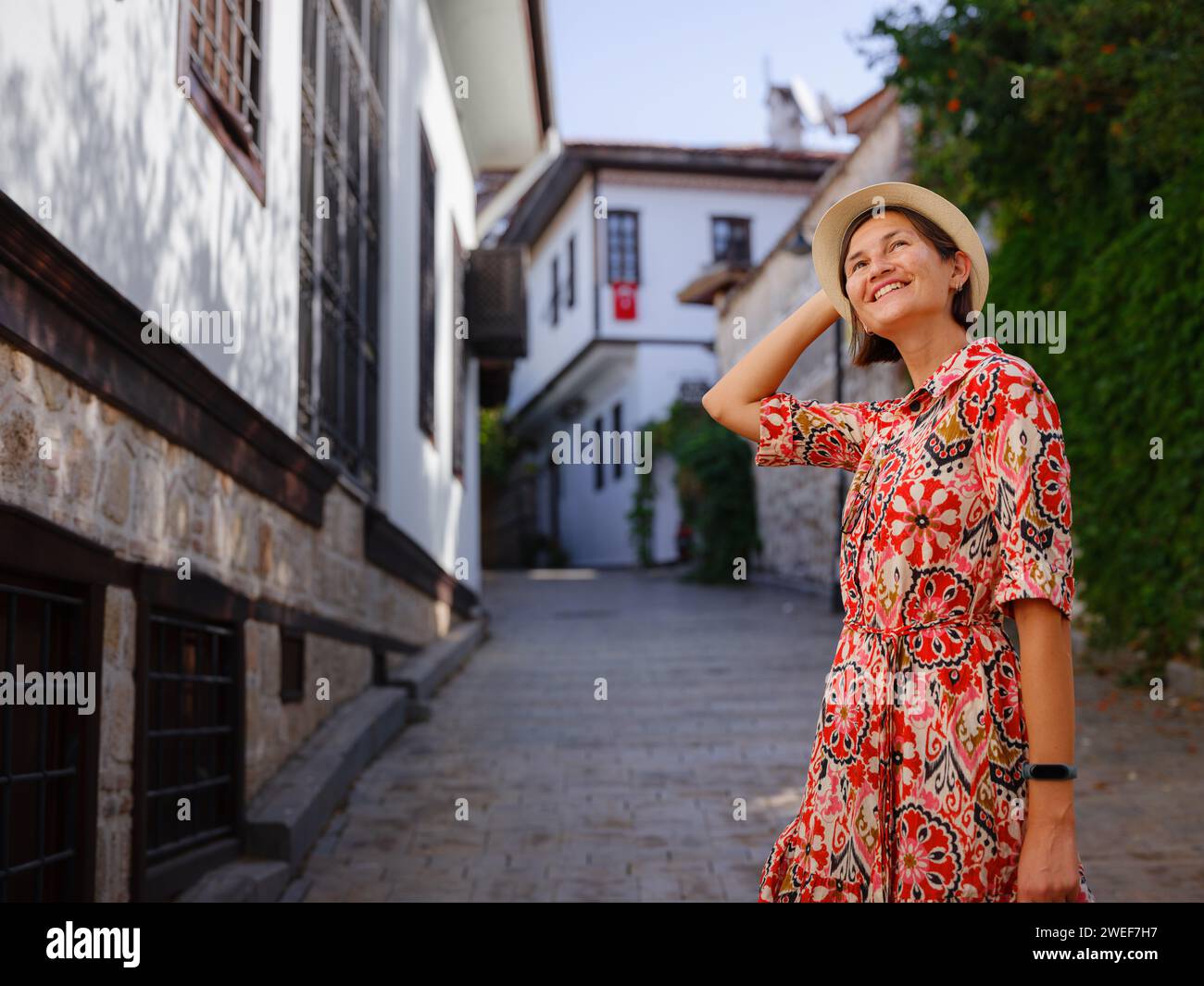 female summer travel to Antalya, Turkey. young asian woman in red dress walk through old town ...