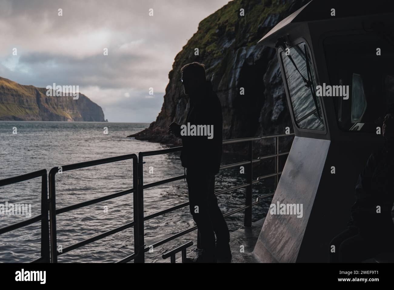 Silhouette of a man sailing on a boat and standing near body of water ...
