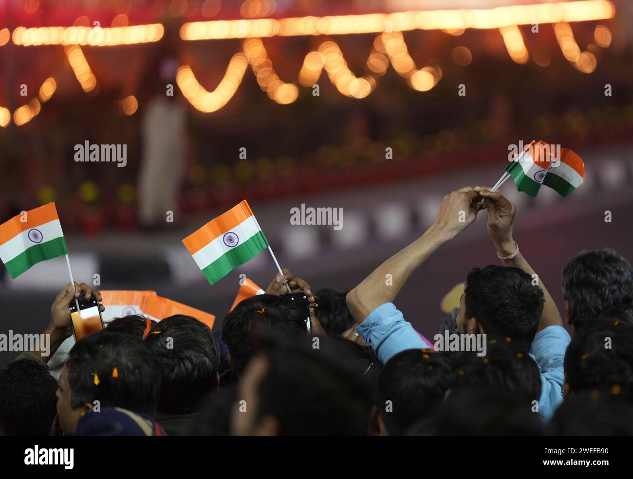 People wave the Indian national flags as they watch French President ...