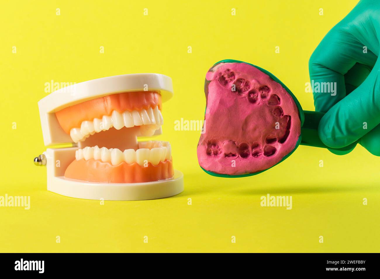 A doctor's hand in a green medical glove holds a dental spoon with an ...