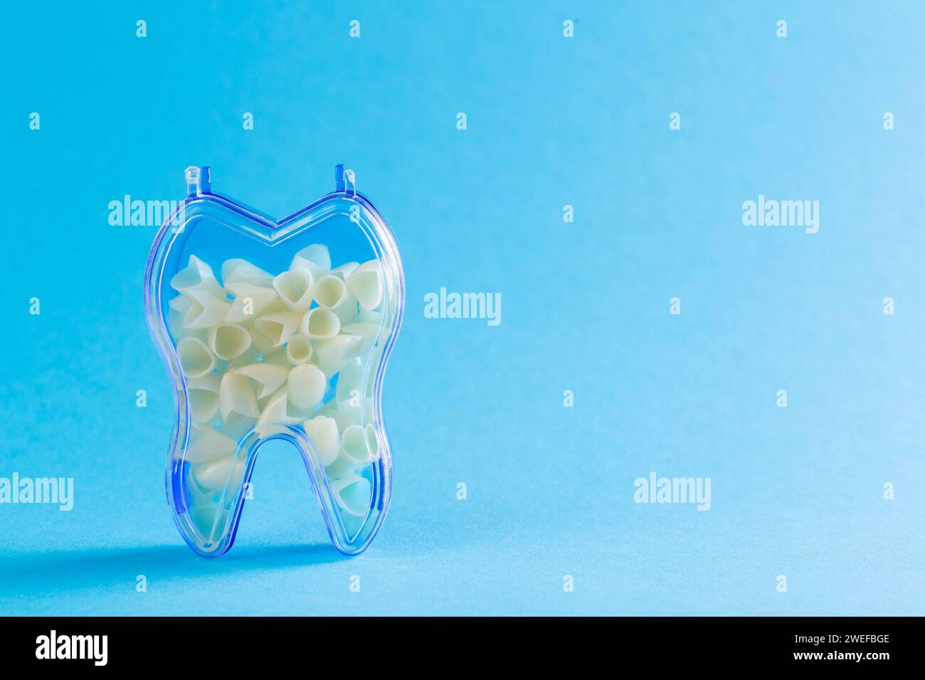 Dental crowns in the shape of a tooth on a blue background. The concept ...