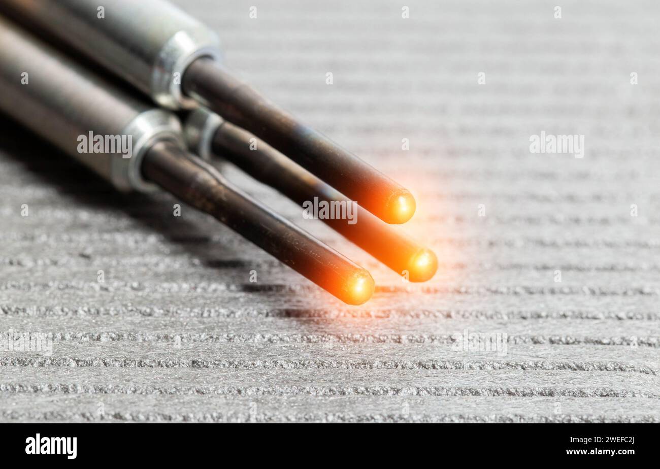 Serviceable modern ceramic glow plugs on a gray background. Orange glow ...