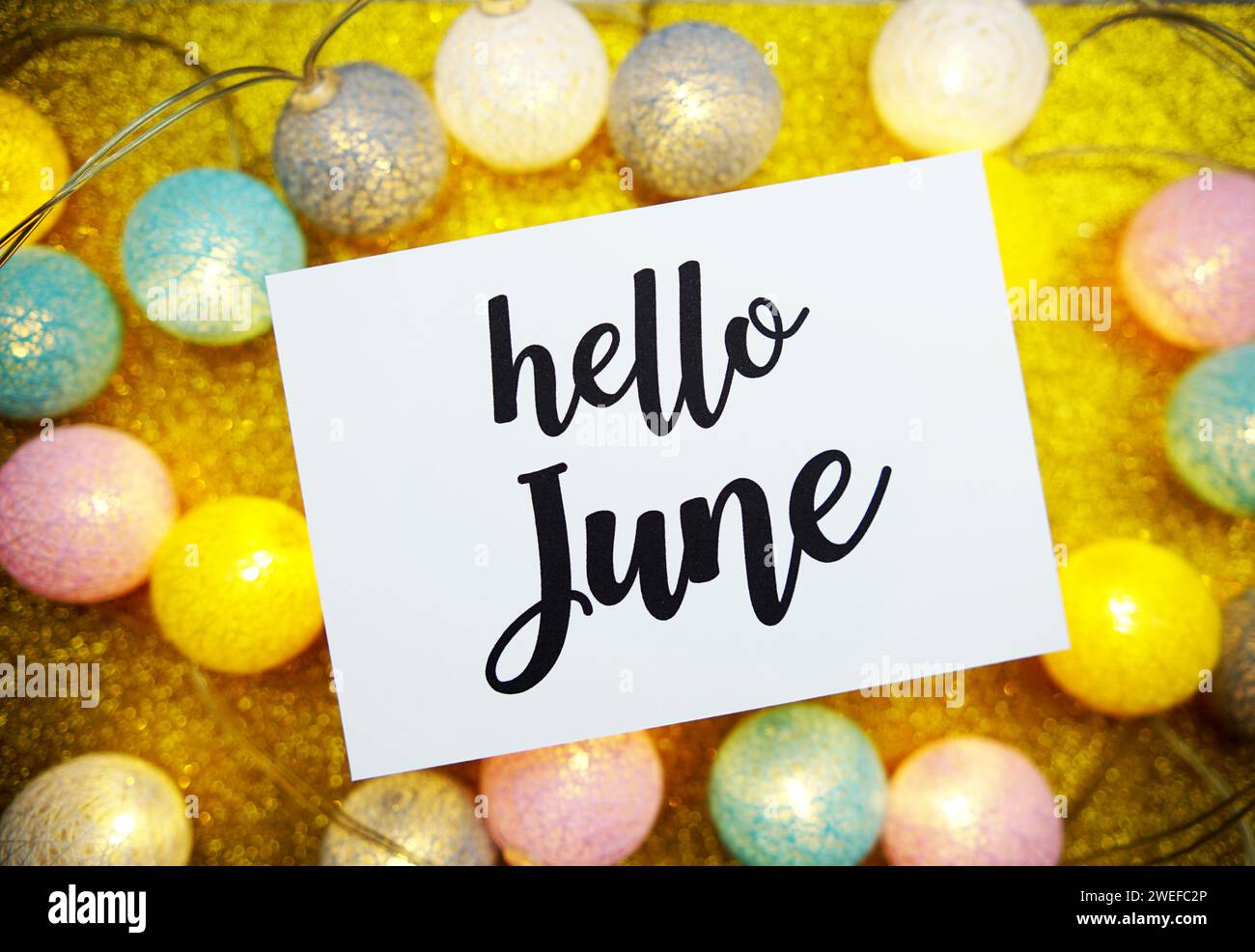 Hello June text on paper card with LED cotton balls decorate on yellow ...