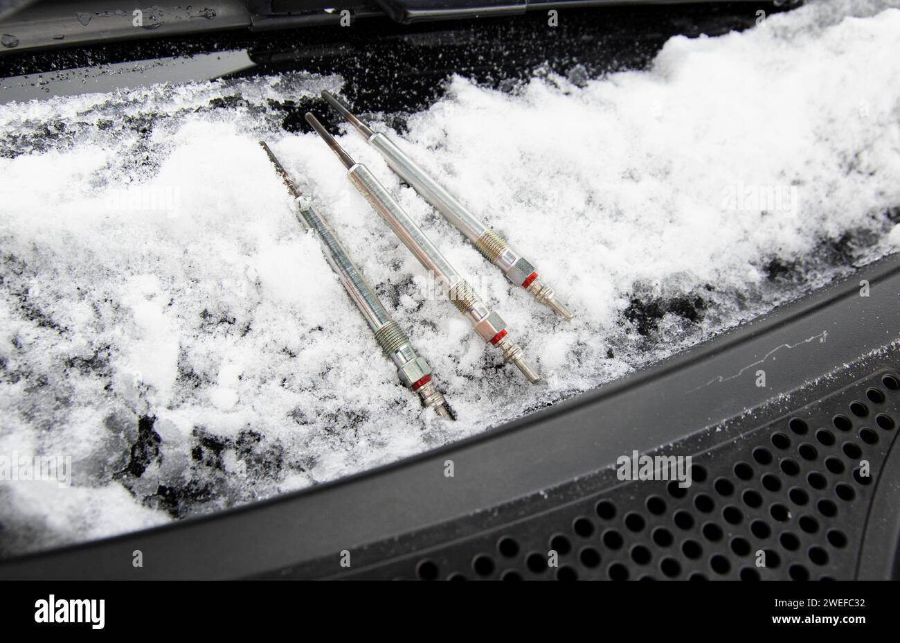 Rod ceramic glow plugs on an icy car hood in winter. Heating elements ...
