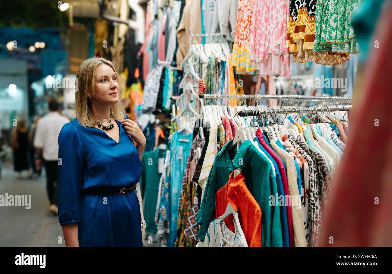 Woman choosing a clothes at the evening bazaar Stock Photo - Alamy
