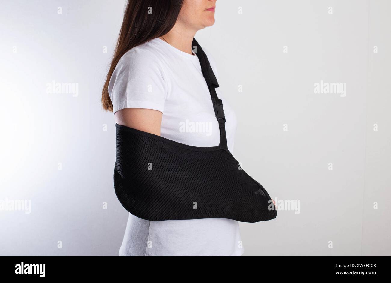 A girl in white with a fixing black bandage on her arm after an injury ...