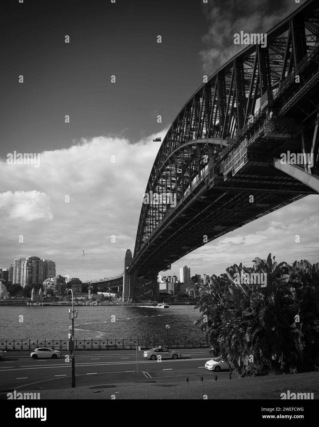 A Sleek And Modern Bridge Structure Arches Over A Serene Body Of Water
