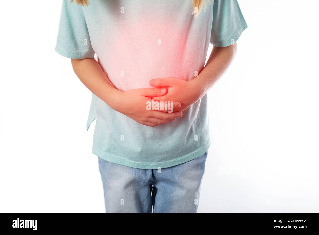 A seven-year-old girl in a green T-shirt holds her inflamed red stomach ...