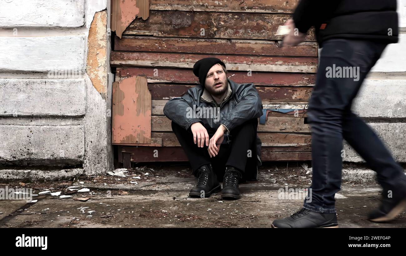 Illegal caucasian immigrant sits on ground. Below poverty line ...