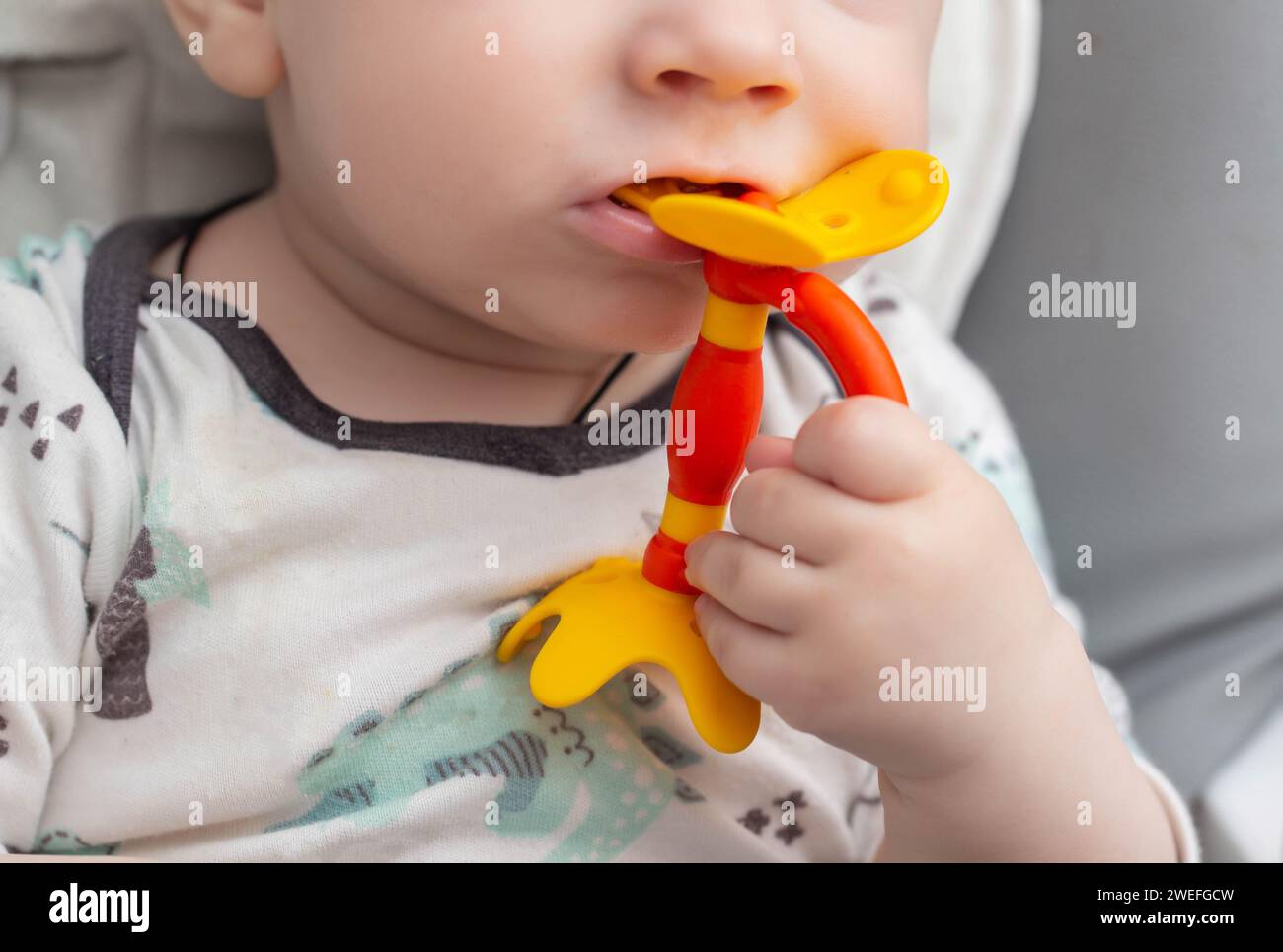 Portrait of a child who bites a multi-colored toy massager for teething ...