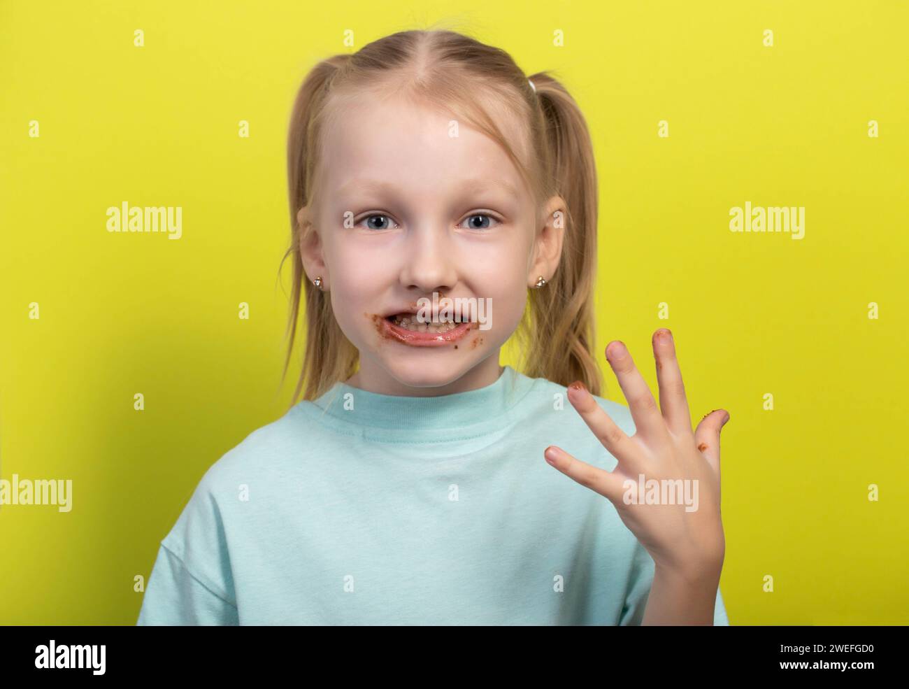 A seven-year-old girl with a mouth dirty from chocolate on a yellow ...