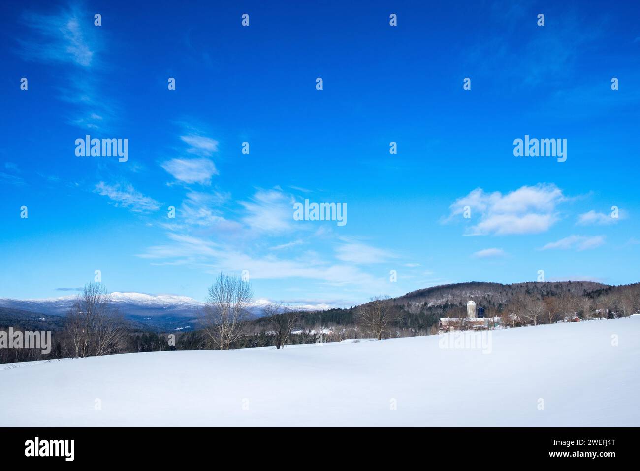 A barn and silo in a snowy field in East Montpelier, Vermont, USA, a ...