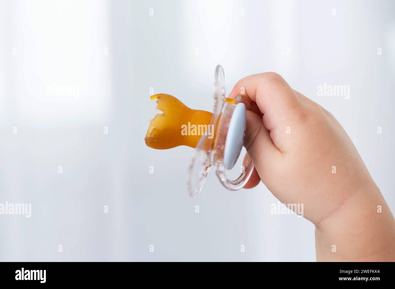 A baby's pacifier is chewed and torn in a baby's hand, close-up ...