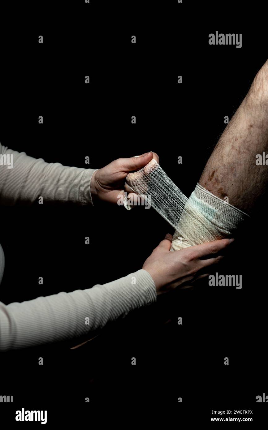 Nurse removing a bandage from a male patient with a black background ...