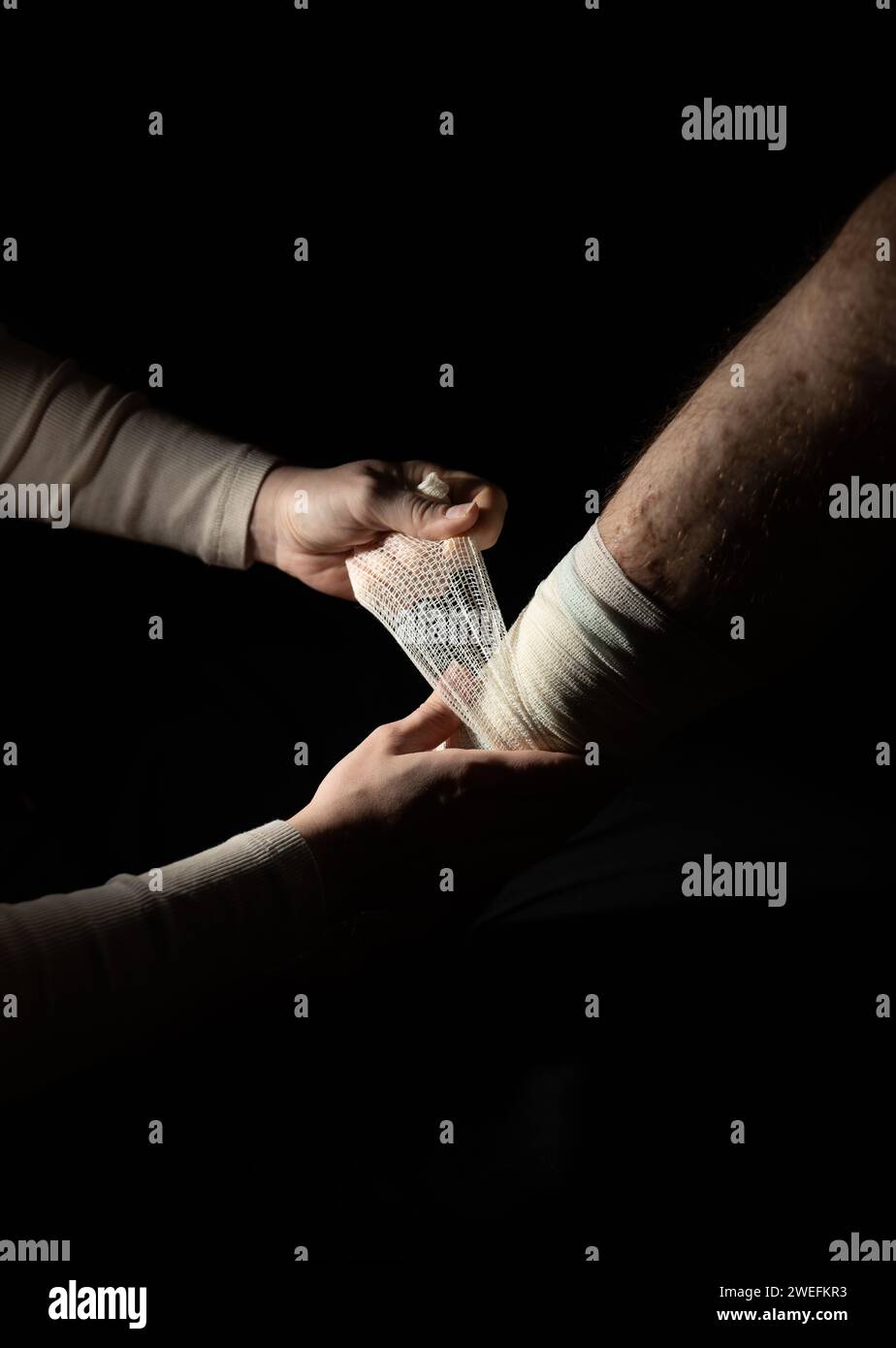 Nurse removing a bandage from a male patient with a black background ...