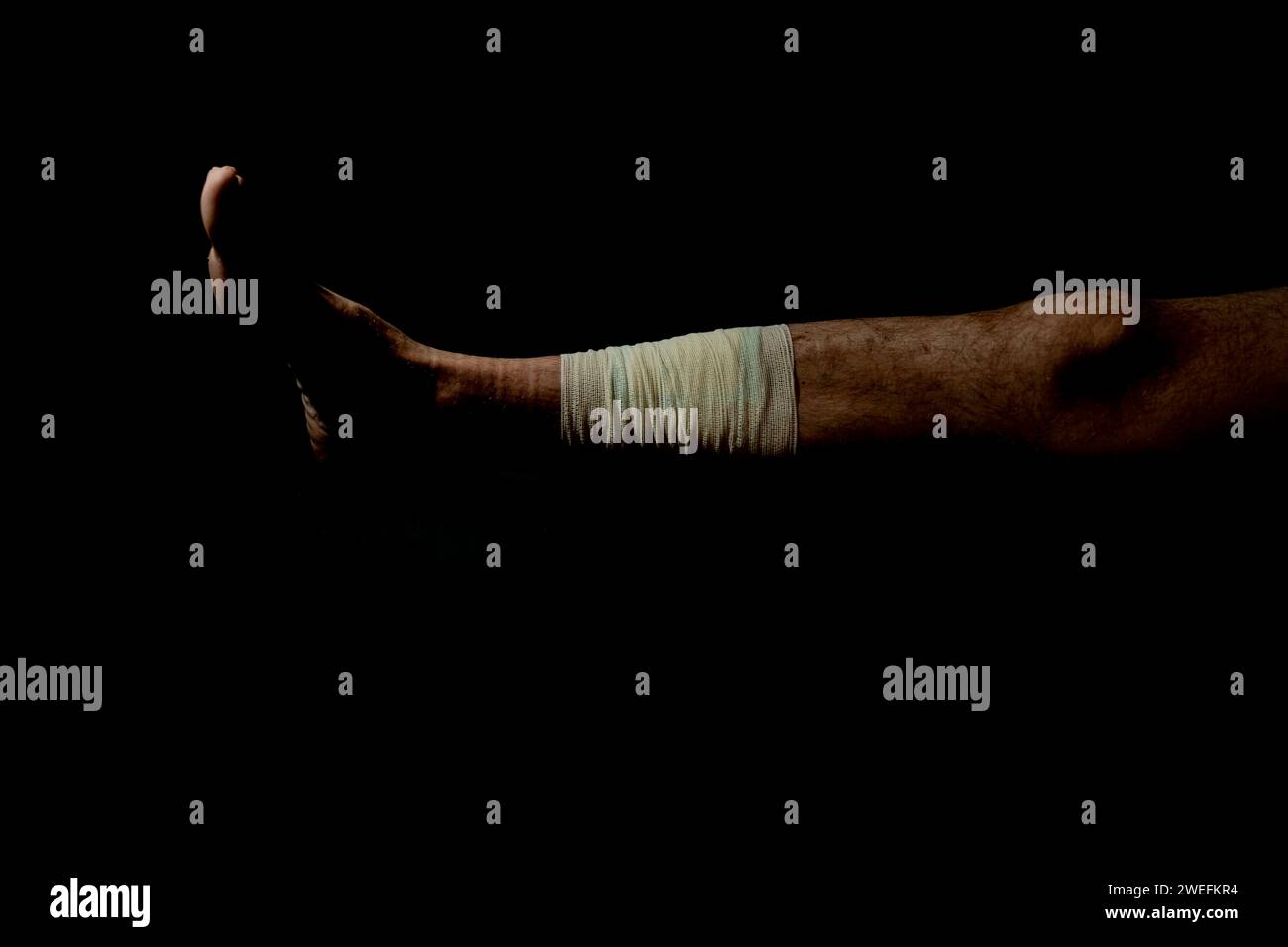 Male laying with bandage on his right leg. Black background Stock Photo ...
