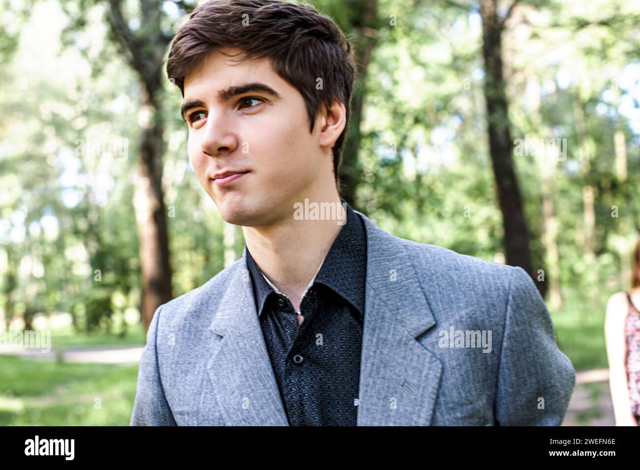Frontal portrait of a smiling young man not looking at the camera in a ...
