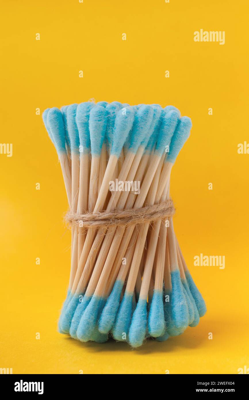 A bunch of blue bamboo cotton swabs buds sticks on a yellow background ...