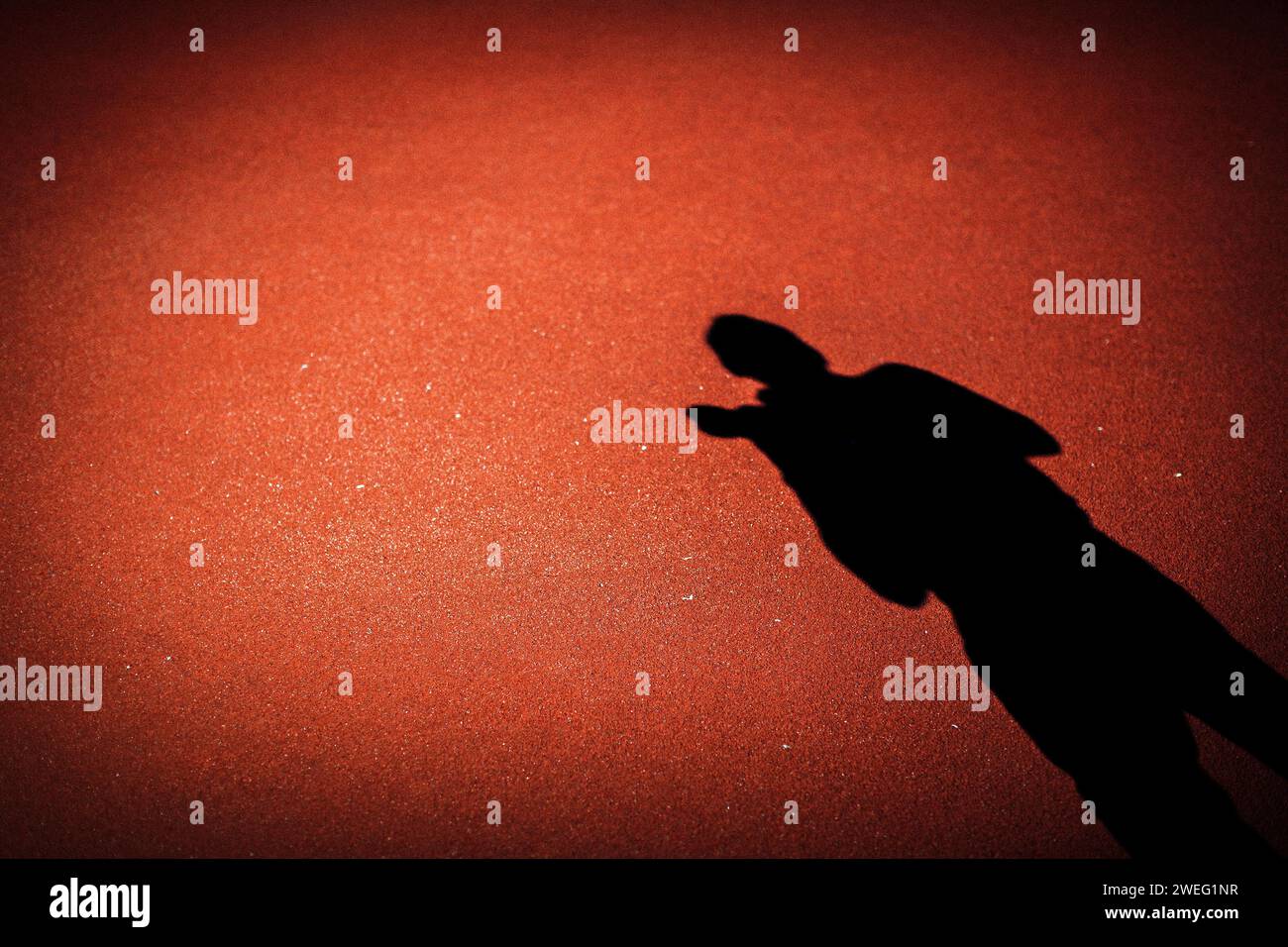 Sport photographer unrecognizable person shadow on athletic red track ...