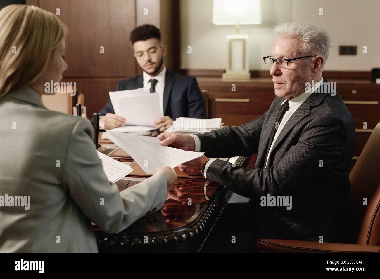 Mature businessman passing paper to businesswoman, their colleague ...