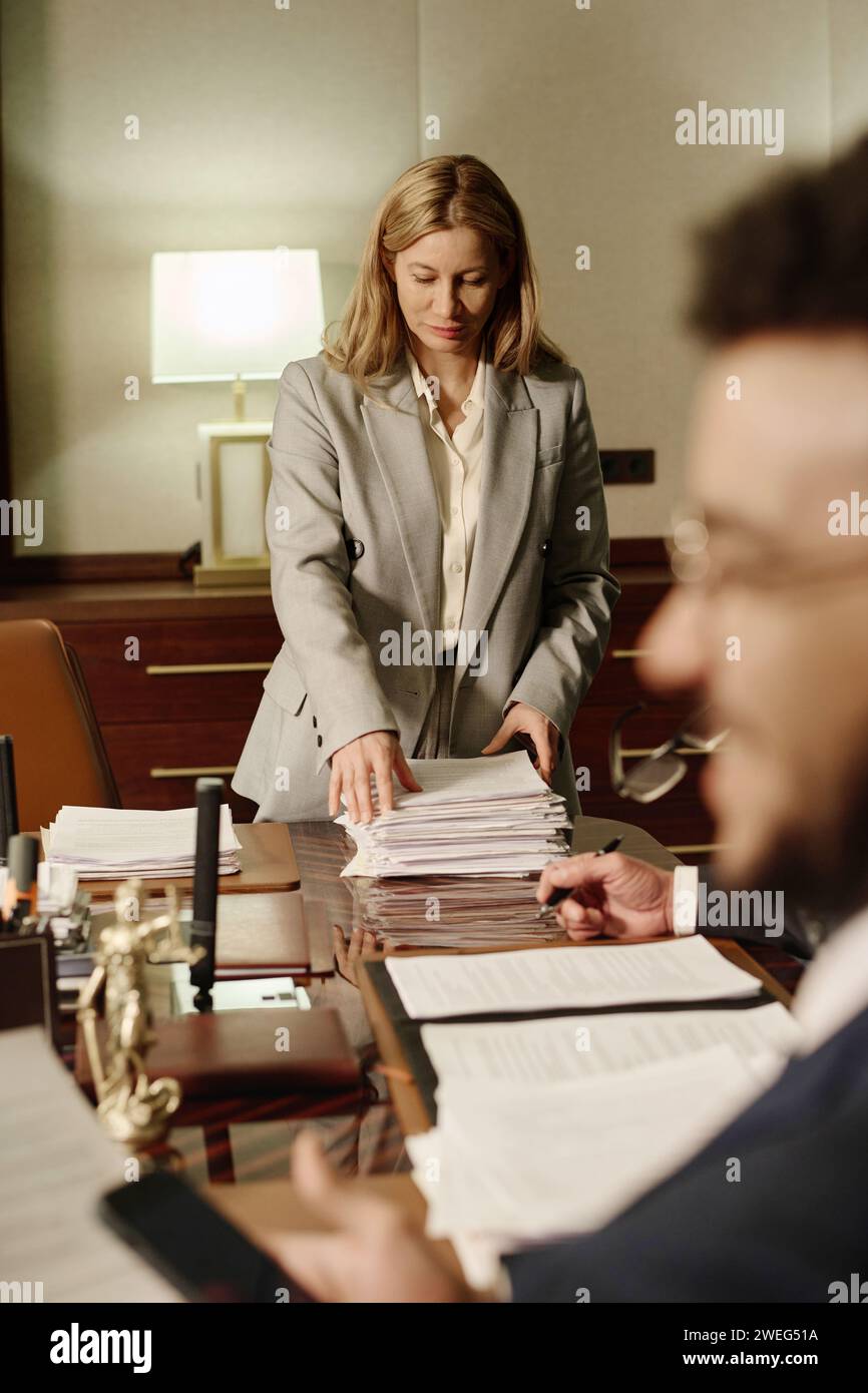 Female attorney in suit arranging pile of documents on her workplace in ...