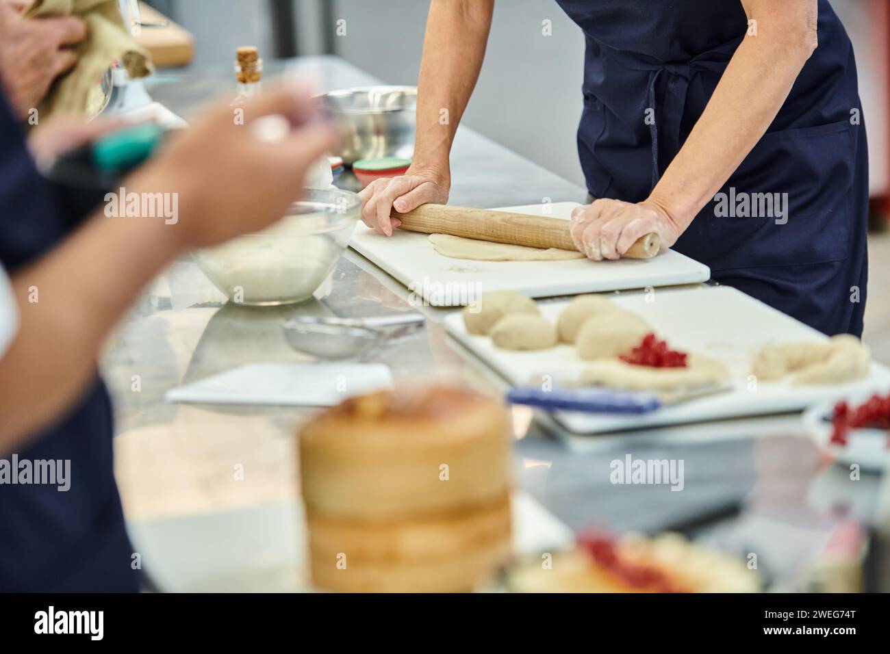 focused view of cropped mature woman using rolling pin next to blurred ...