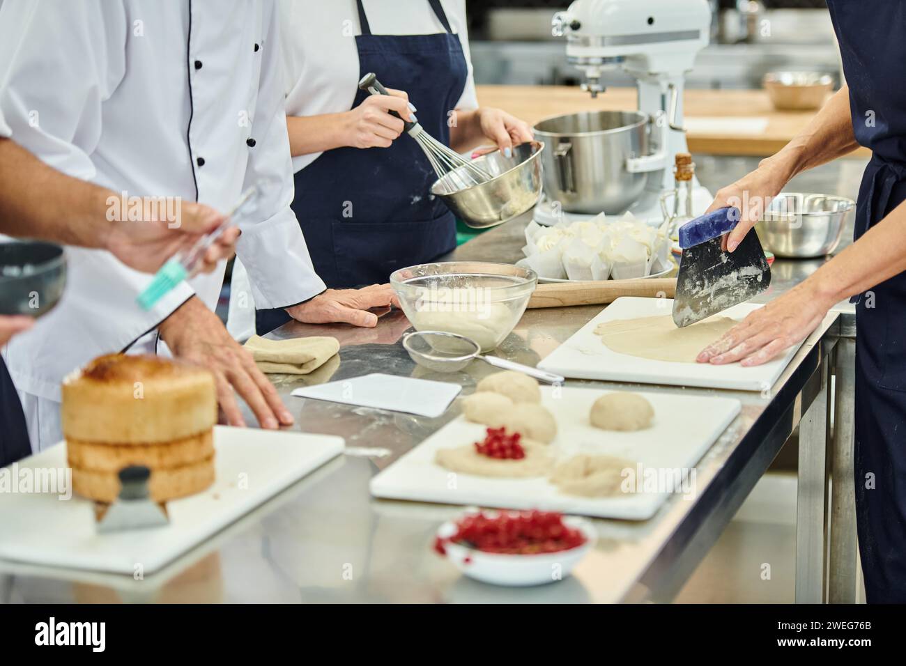 cropped view of hard working chefs and chief cook working with dough on ...