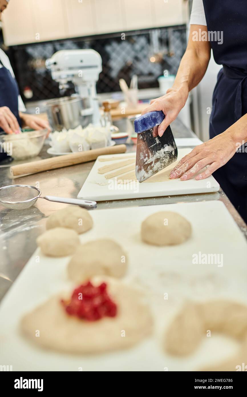 cropped view of mature female chef using cutting board next to her ...