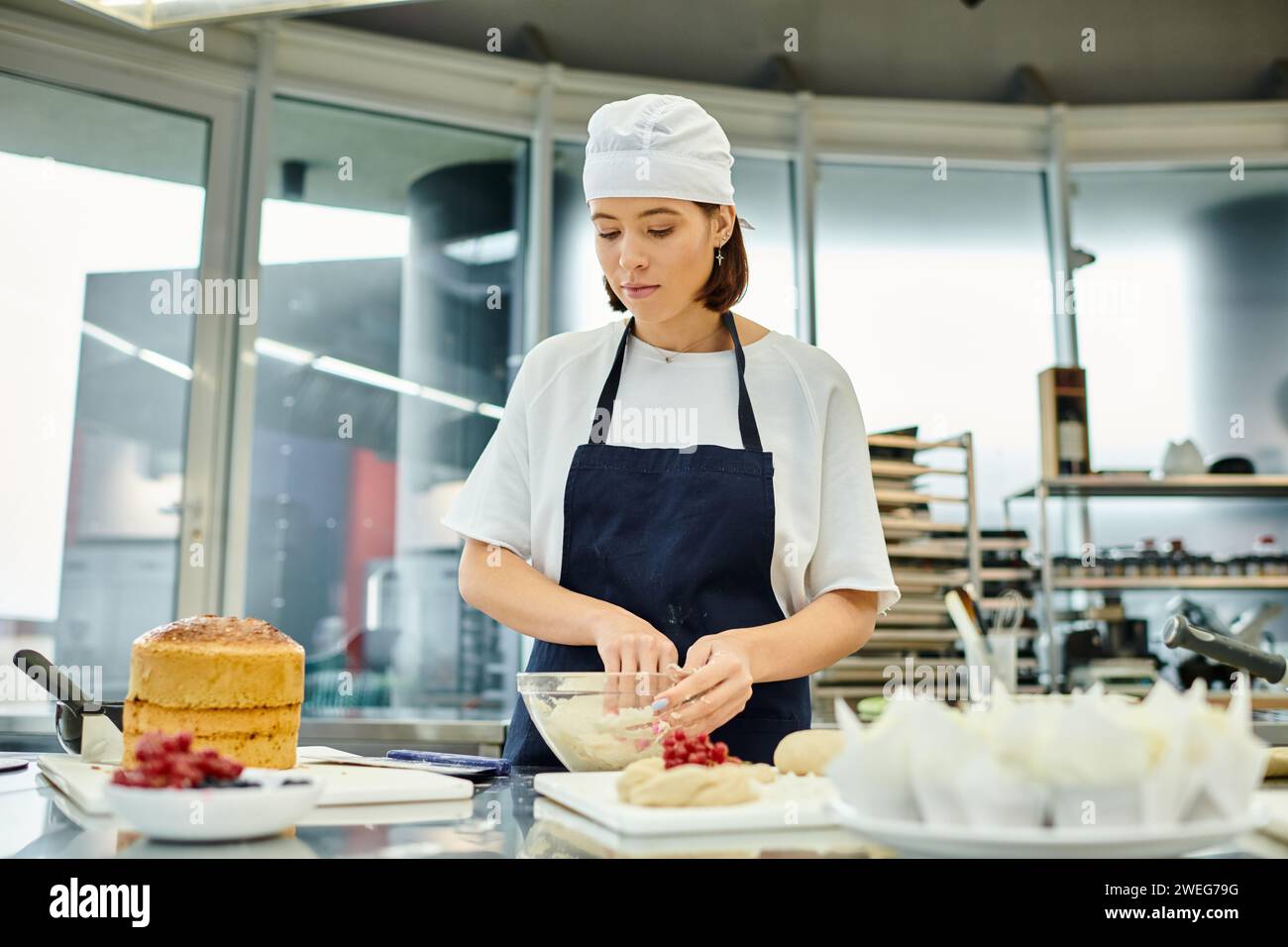 attractive young female chef in toque and apron working hard on kitchen ...