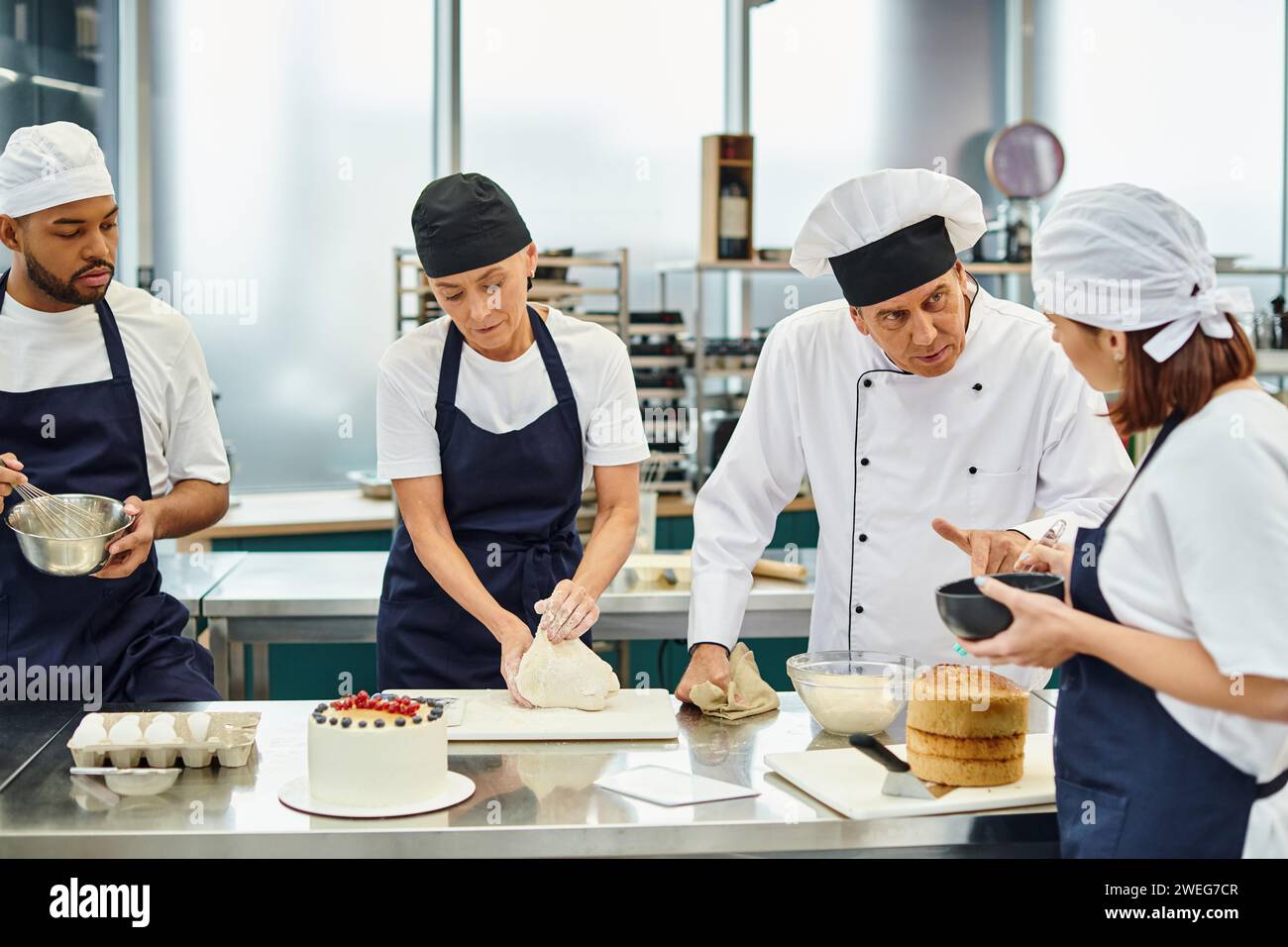 good looking mature chief cook working with his multicultural chefs on ...