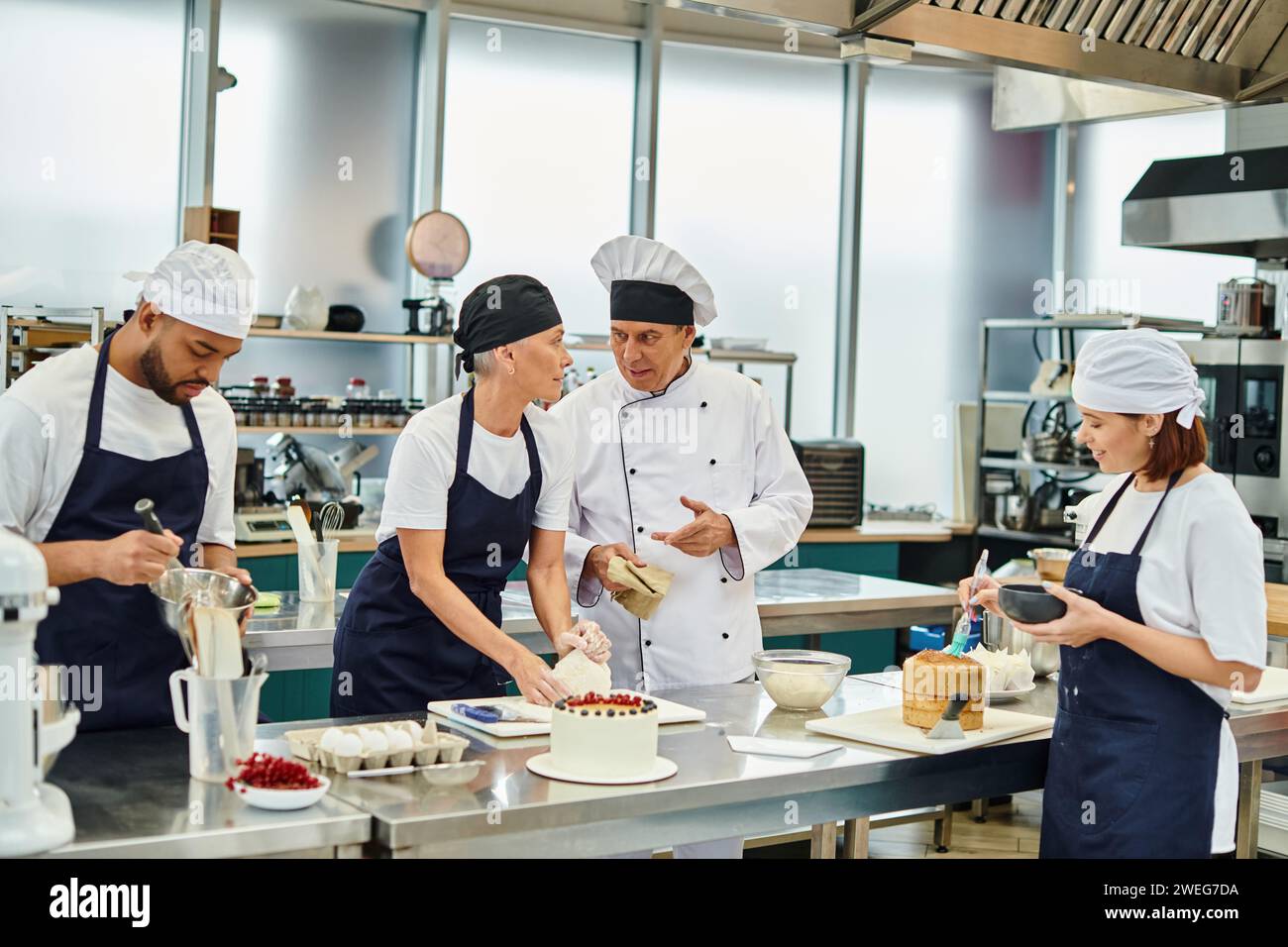 mature chief cook in white hat talking to his chef next to her ...