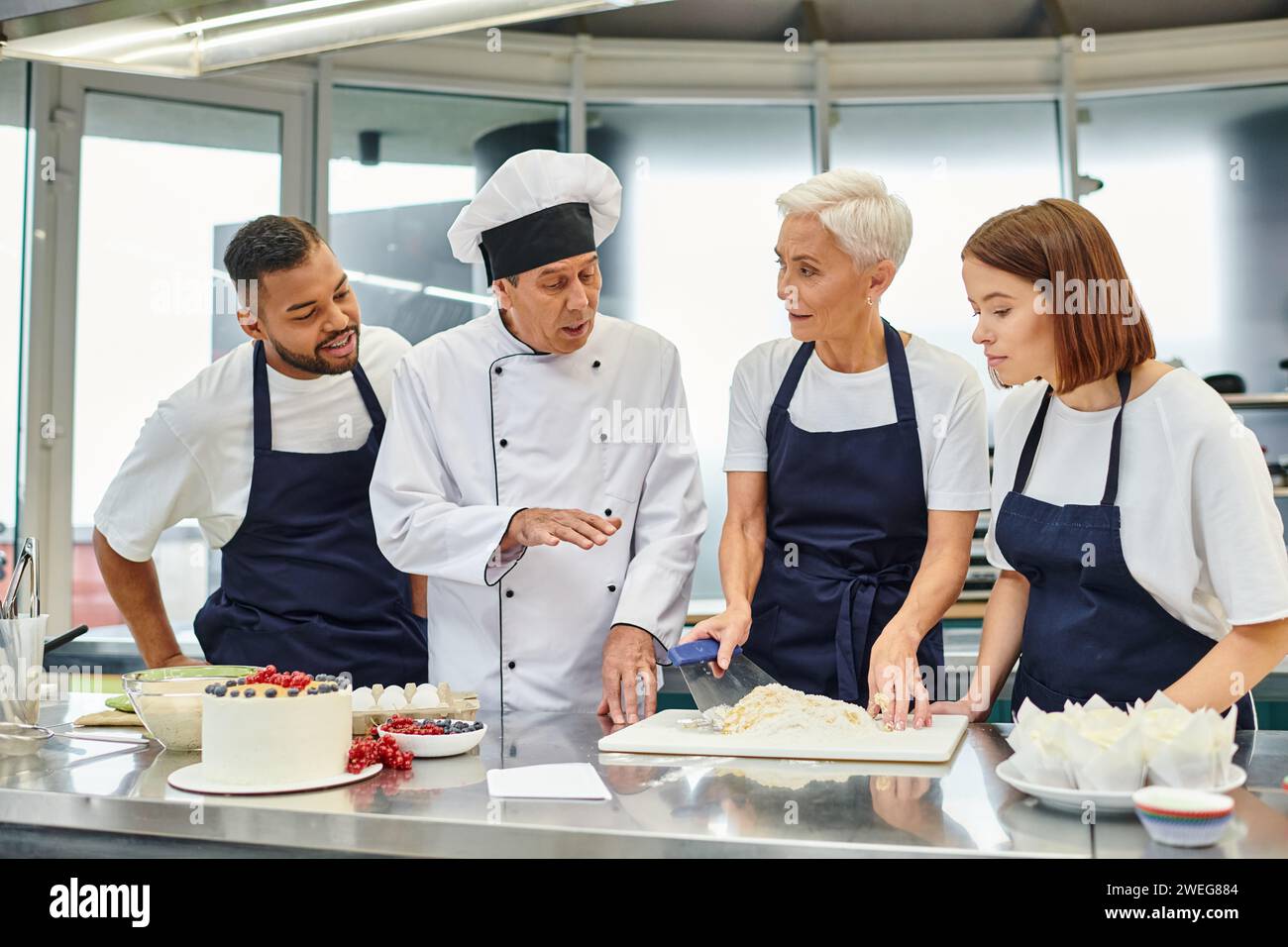 good looking mature chief cook in white hat explaining how to bake to ...