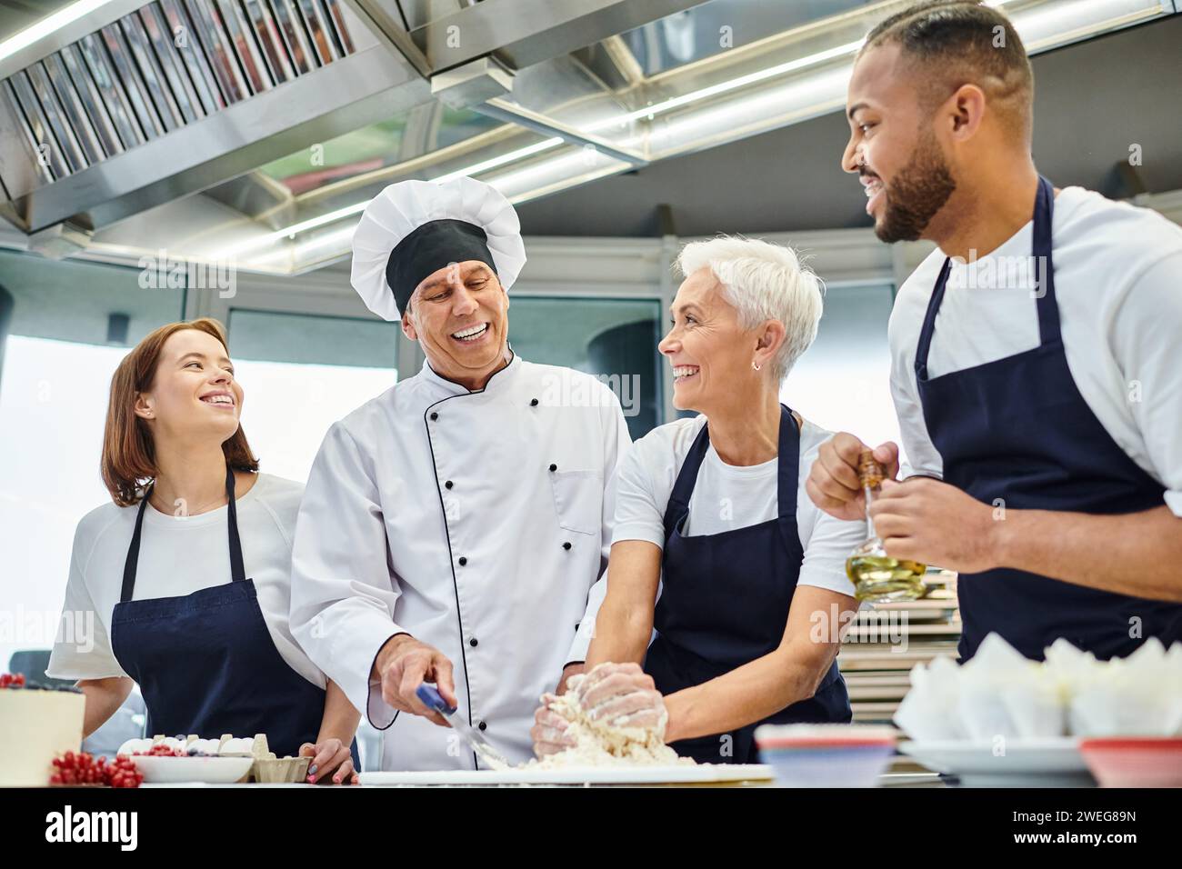 joyful mature chief cook in white hat helping his multicultural chefs ...