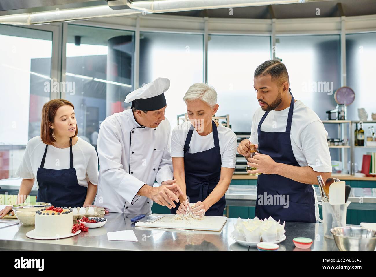 good looking mature chief cook helping his multicultural chefs with ...
