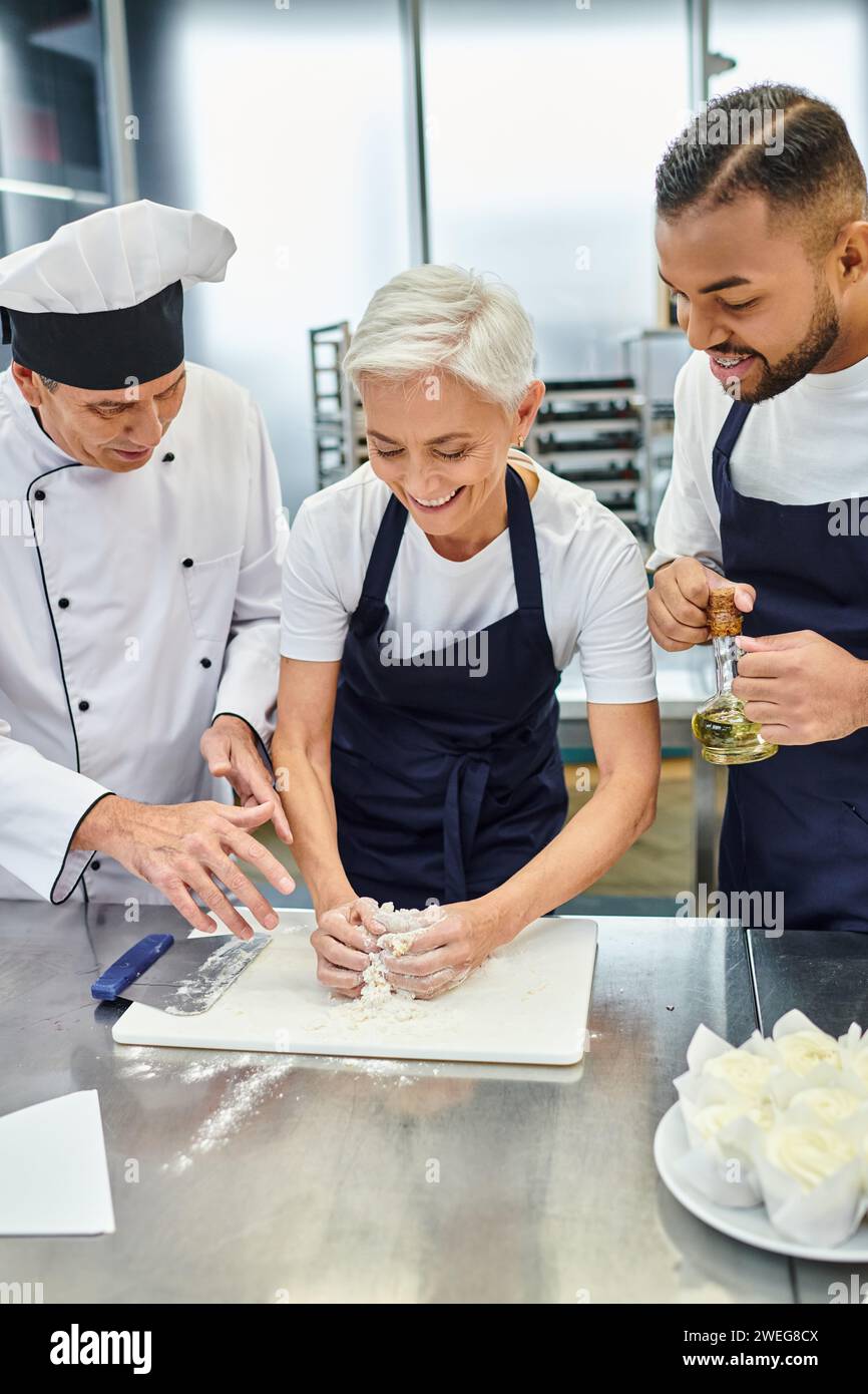 cheerful mature female chef working with dough next to african american ...