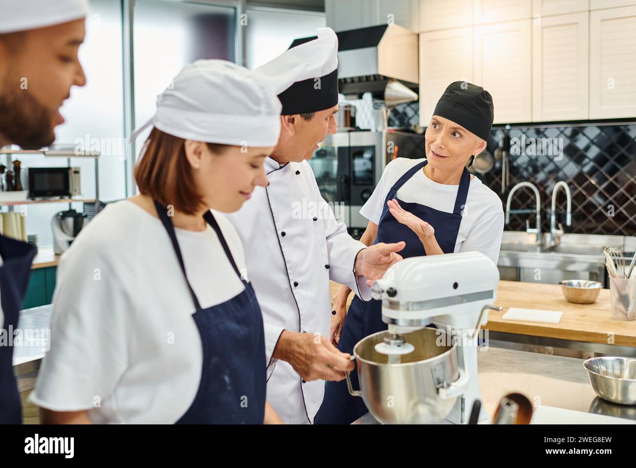 multiracial jolly chefs in blue aprons and toques talking with their ...