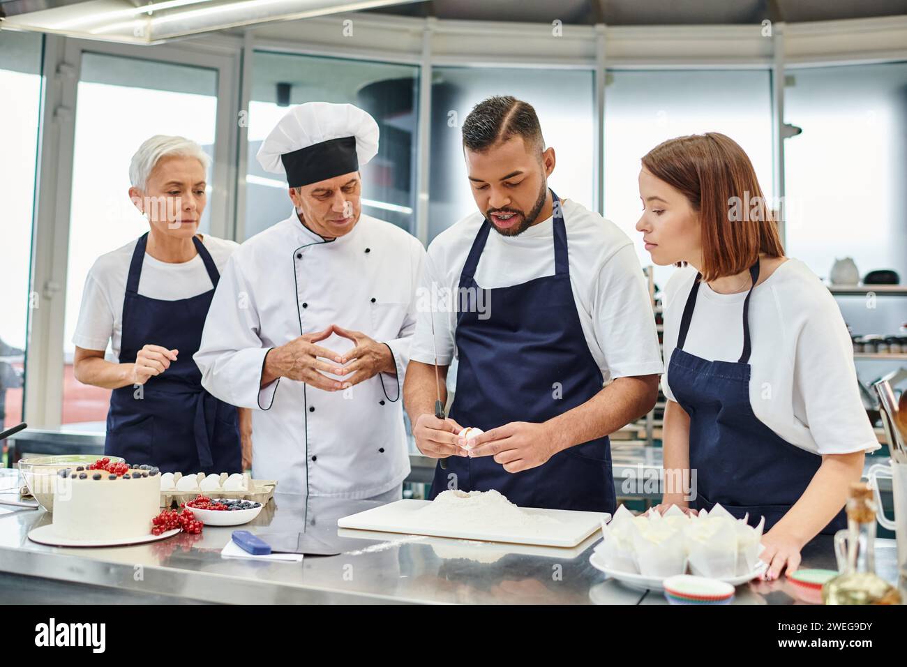 good looking chefs watching their african american colleague breaking egg before baking together ...