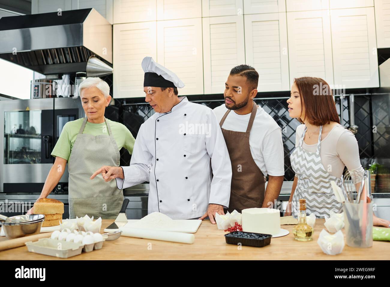 handsome mature chef talking to his multicultural students about how to ...