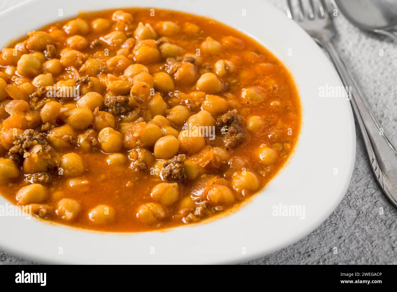 Chickpea stew with minced meat on a white porcelain plate on a stone ...