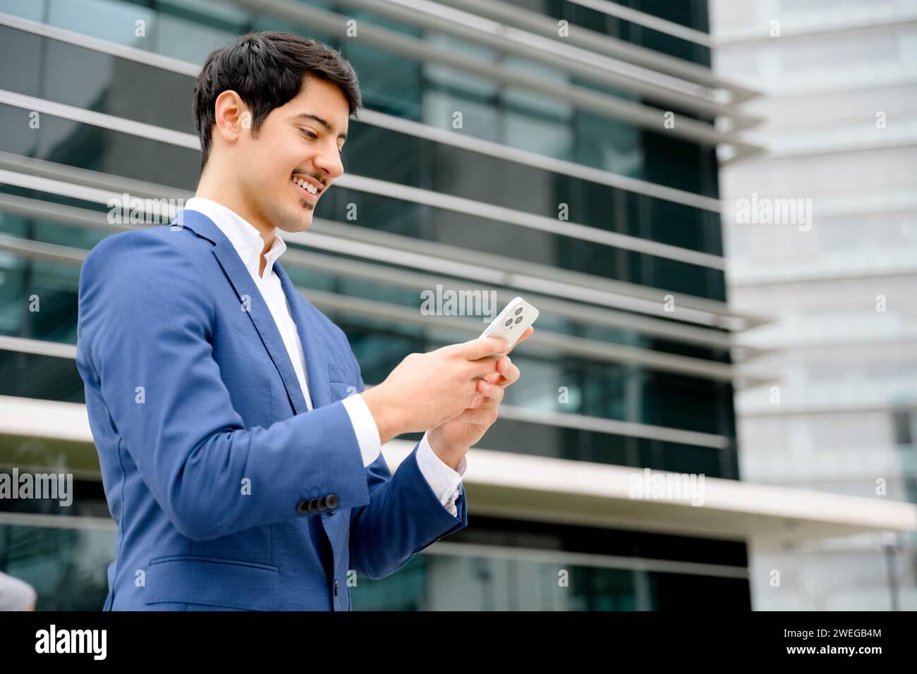 Hispanic entrepreneur happily using his smartphone, the open space ...