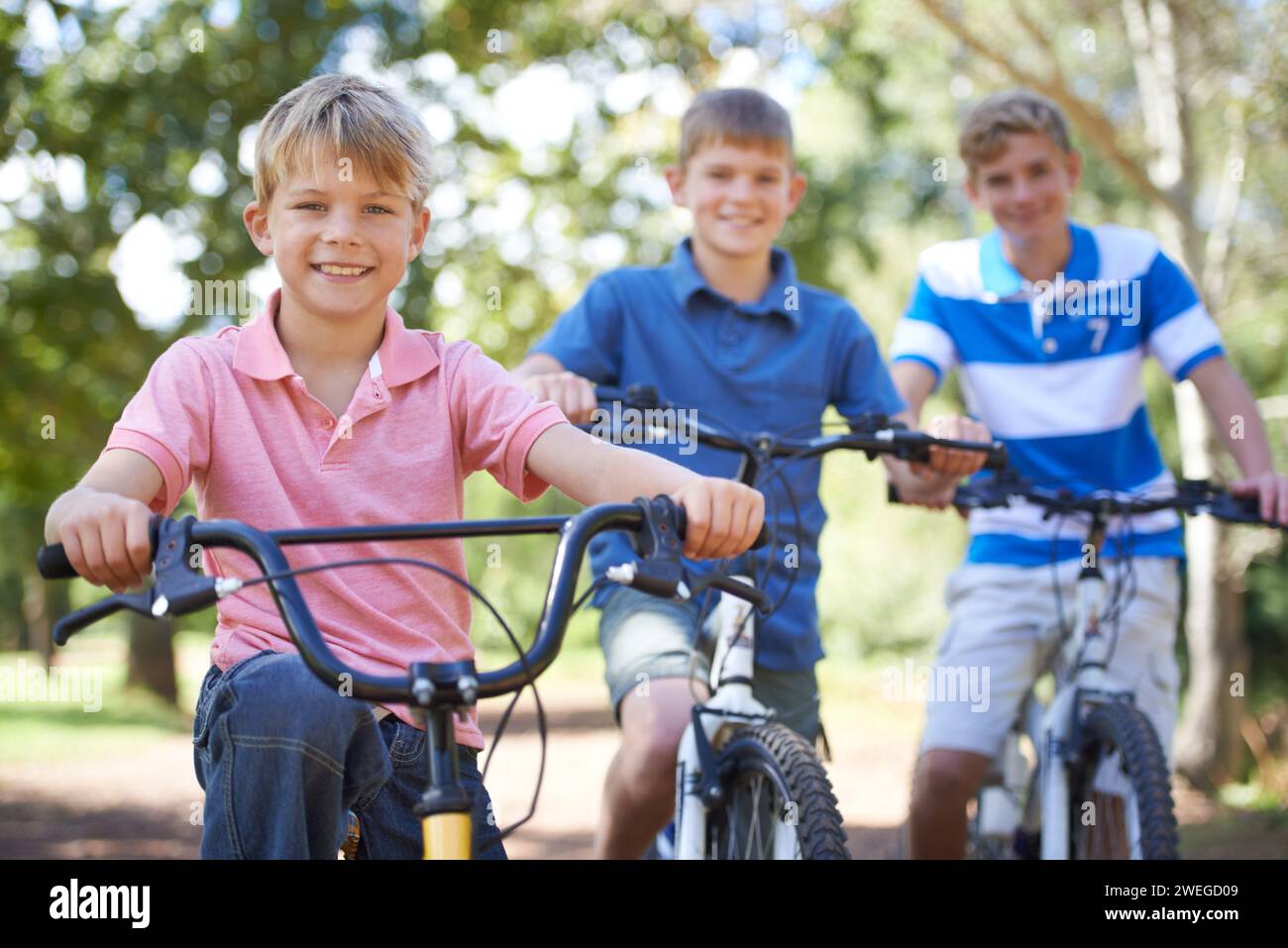 Nature, smile and portrait of kids on bicycles riding in outdoor field ...