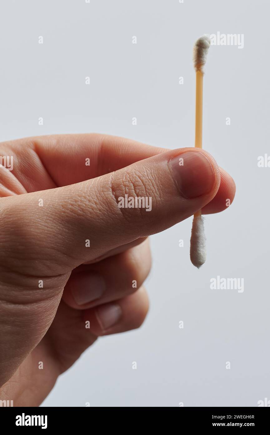 Cotton stick in hand close up view isolated on white studio background ...