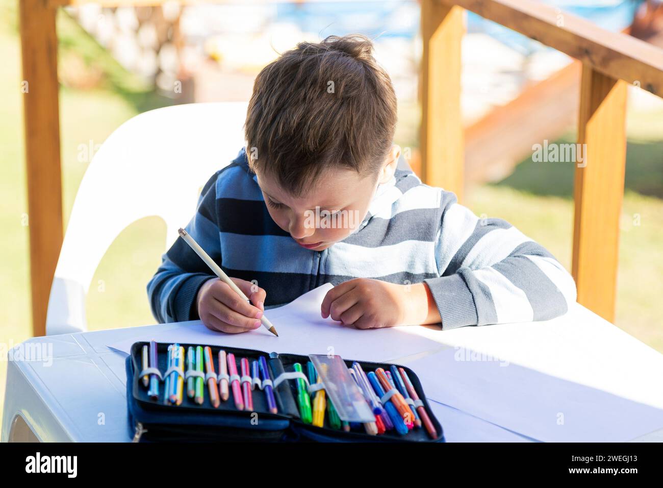 Boy about to draw on a blank paper with graphite pencil. He is outdoors ...