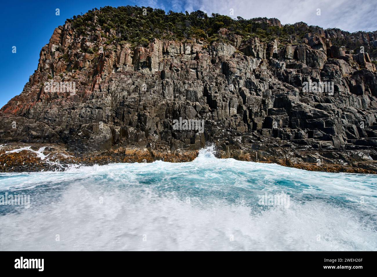 A Rocky island in turquoise water with a cave, surrounded by a rock ...
