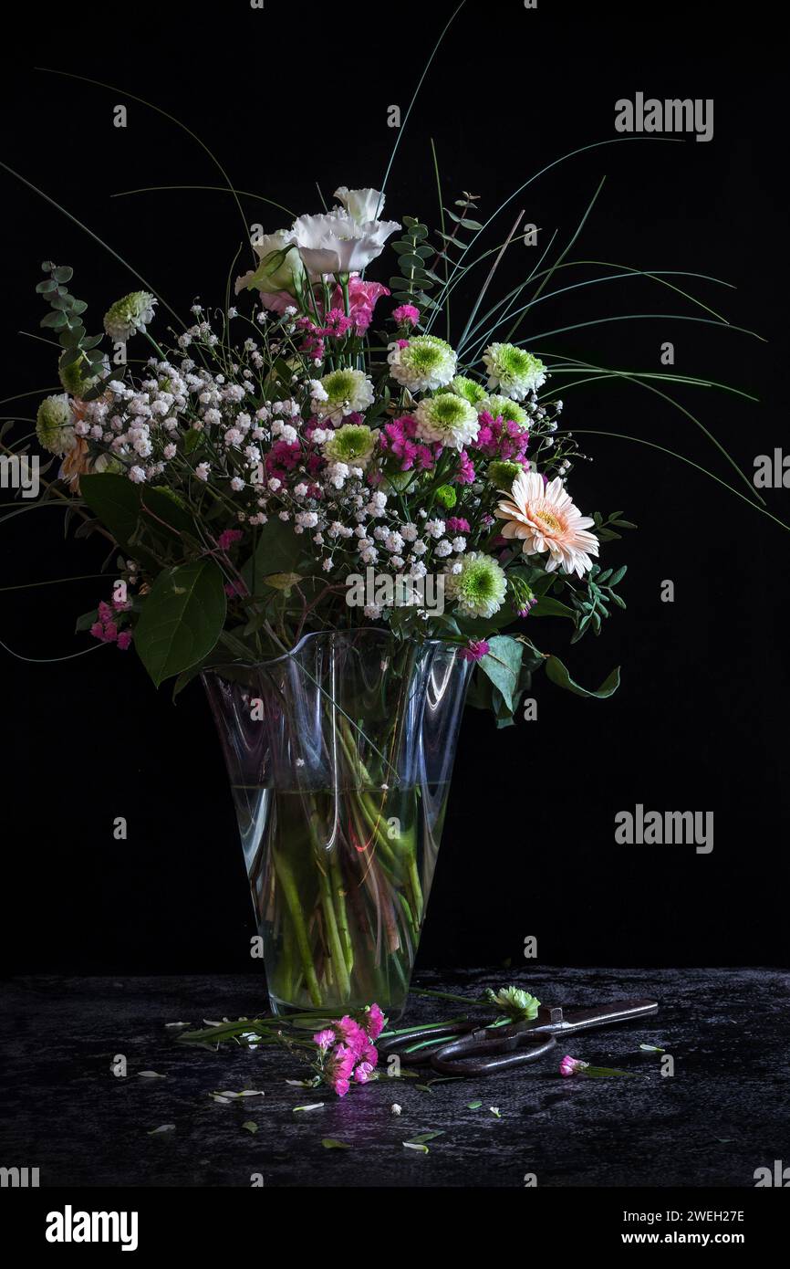 Still life of a flower bouquet in vase with vintage scissors on talbe ...