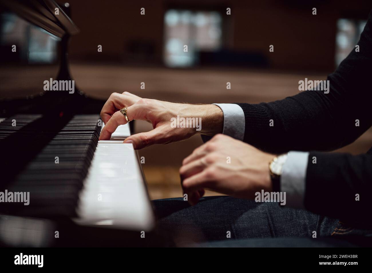 Low angle closeup view of pianist hands in elegant suit playing piano ...