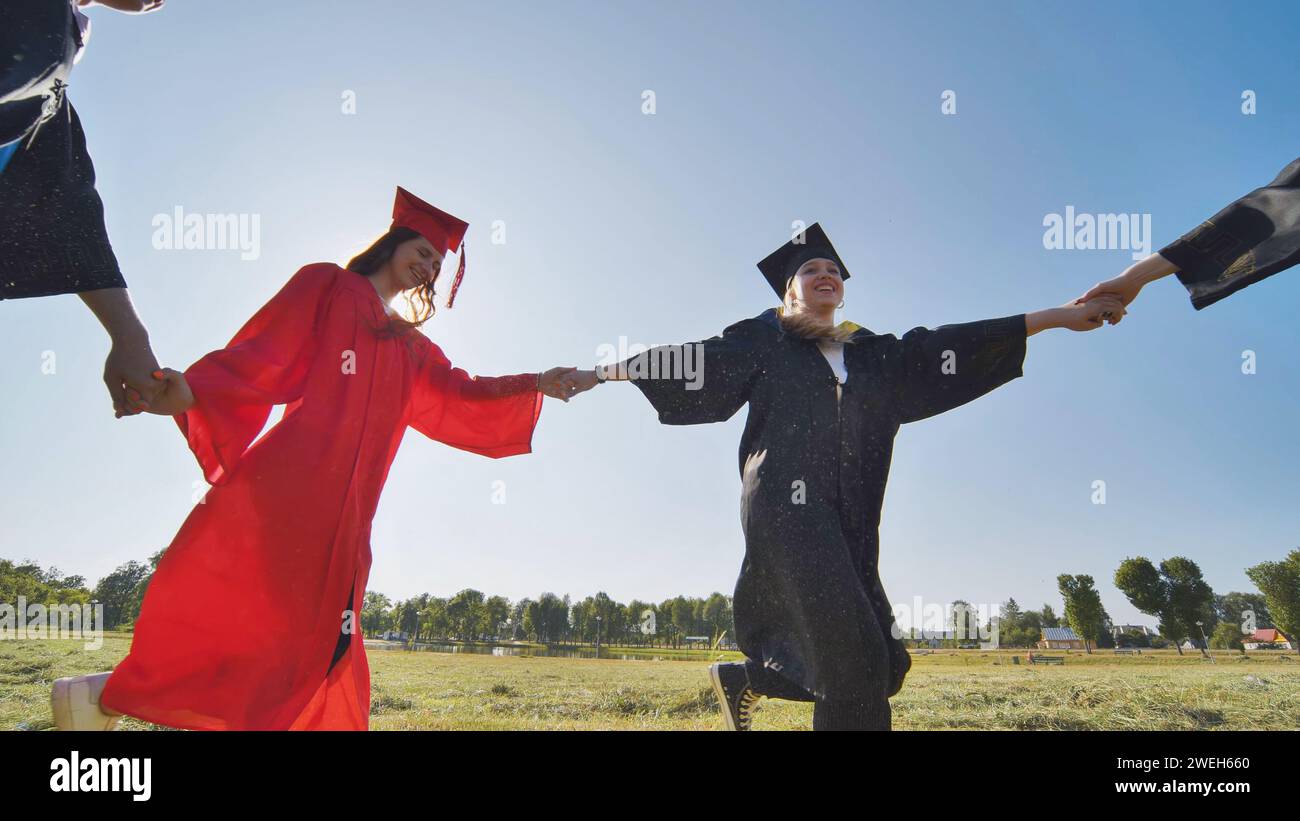 College graduates holding hands run in a round dance Stock Photo - Alamy